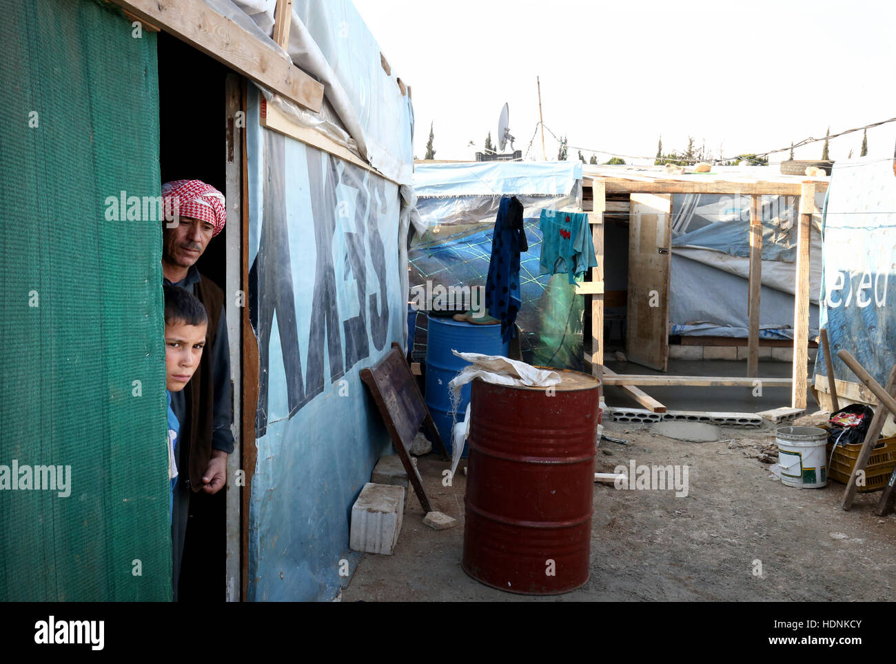 A Syrian refugee man and boy look out from their tent in the refugee ...