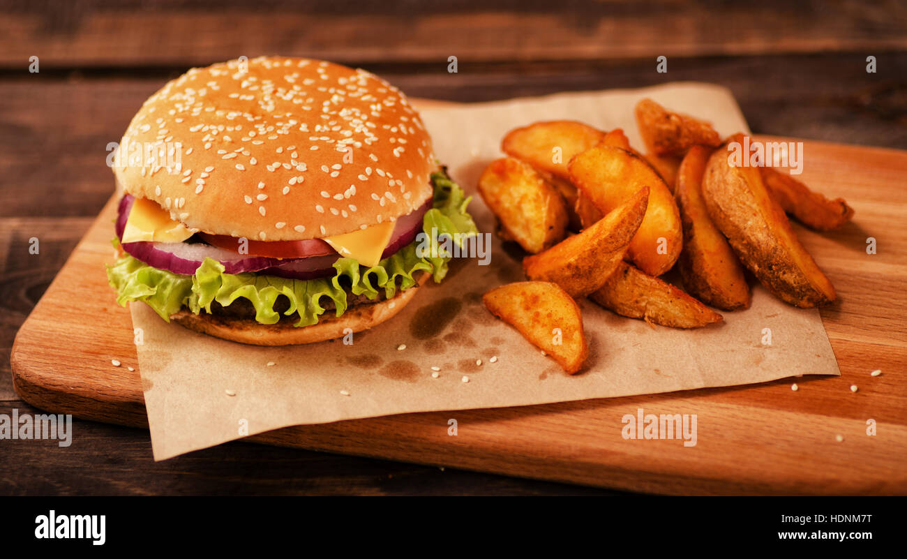 Cheeseburger with potato wedges fried on paper served on restaurant ...