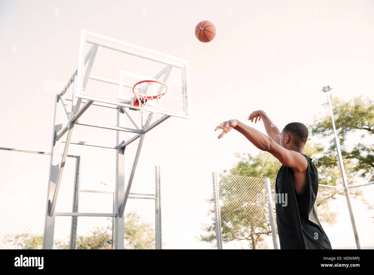Image of african basketball player practicing in the street with trees ...