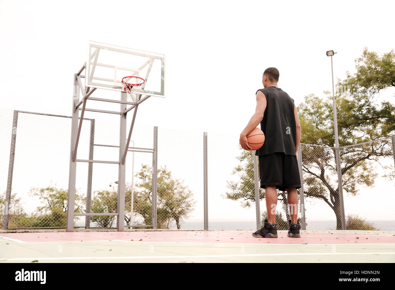 Young african basketball player looking at hoop, shooting at basket ...