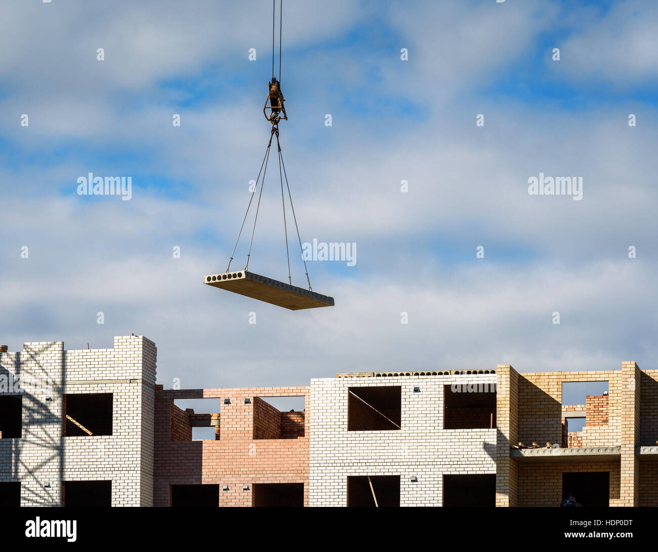 Crane lifting cement block on the background of building under ...