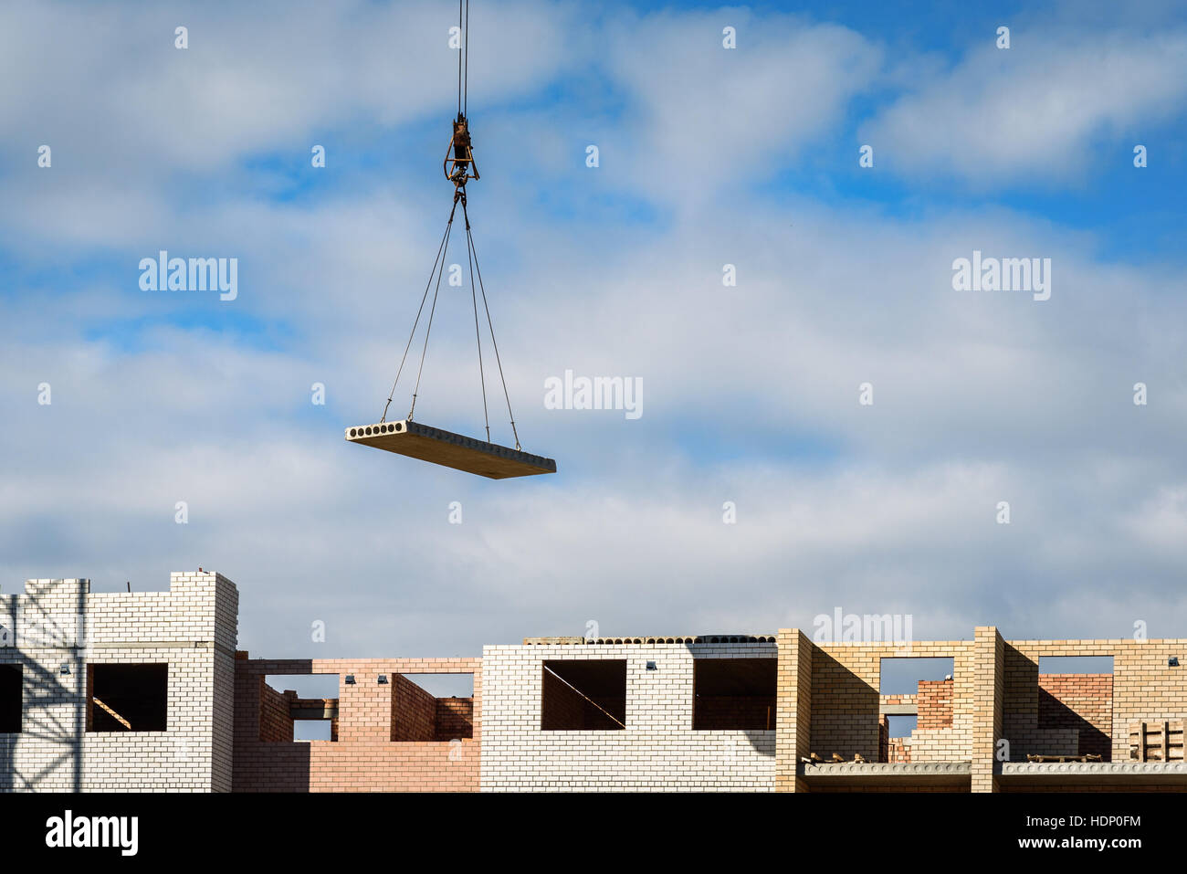 Crane lifting cement block on the background of building under ...