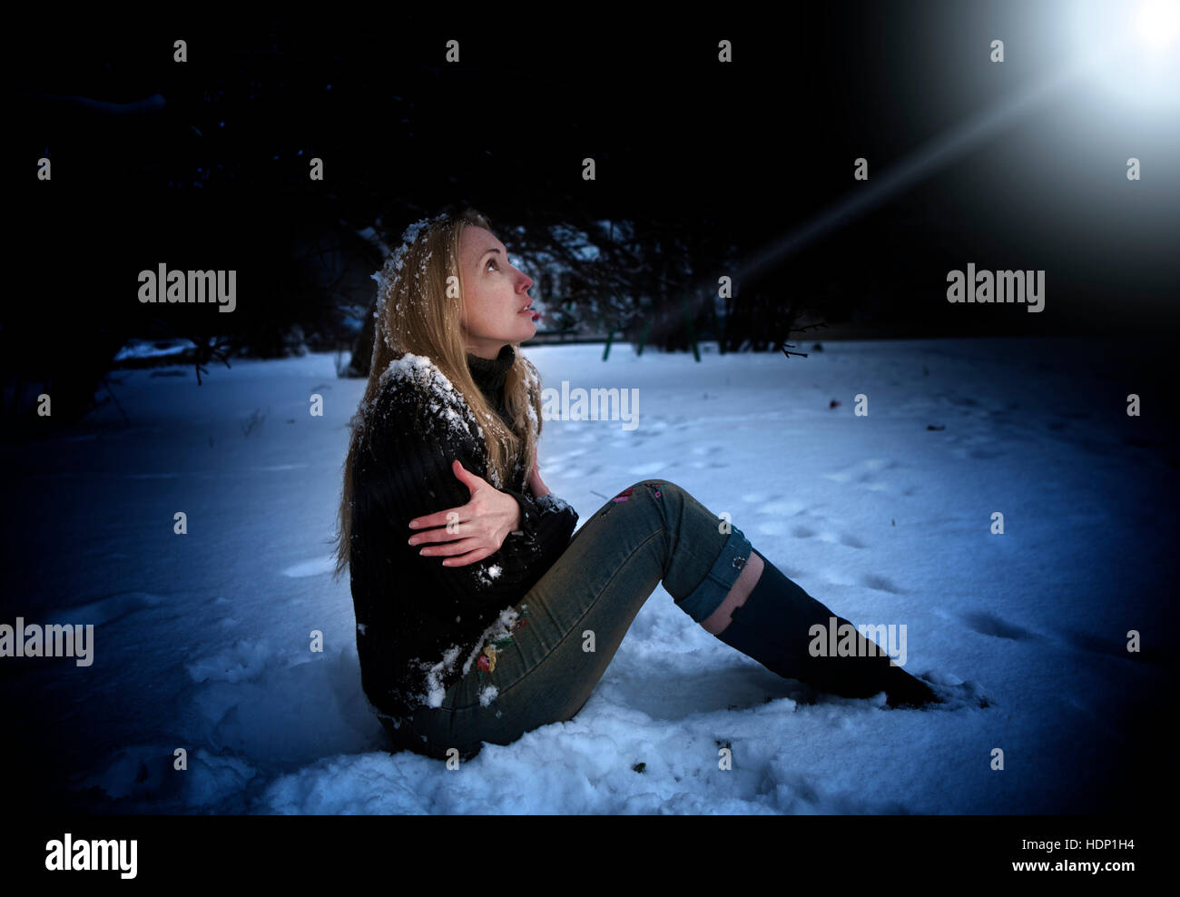 The young beautiful frozen woman sits in snow in the night park Stock ...
