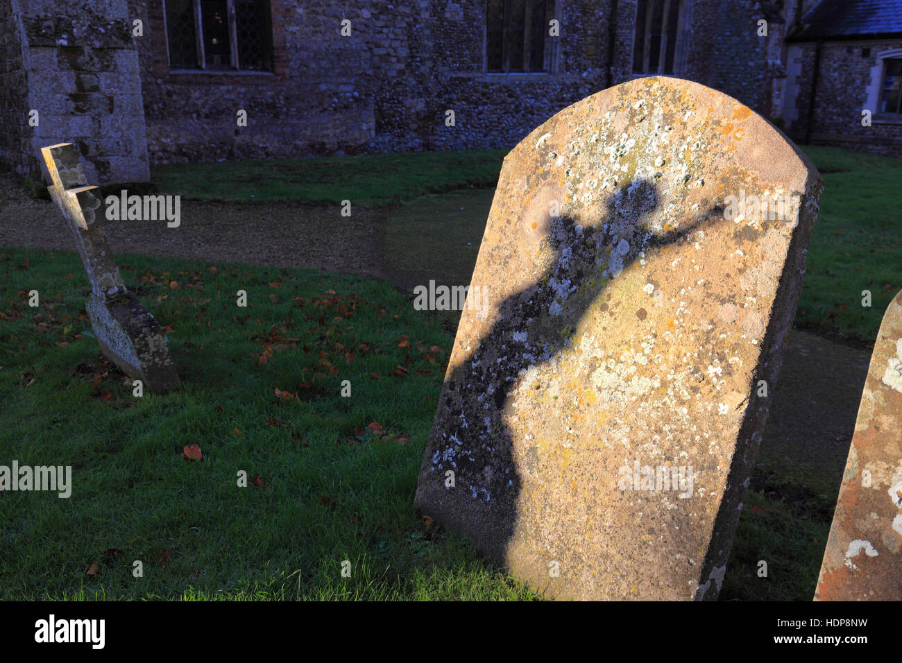 A shadow cast on to a headstone from the statue of an angelic figure in ...