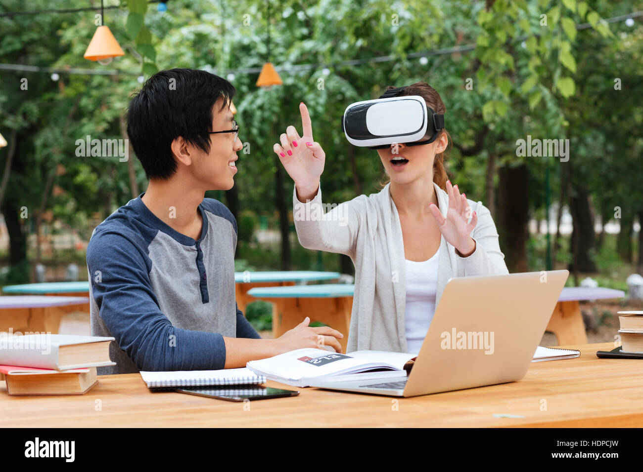 Two cheerful young students studying and using virtual reality glasses ...