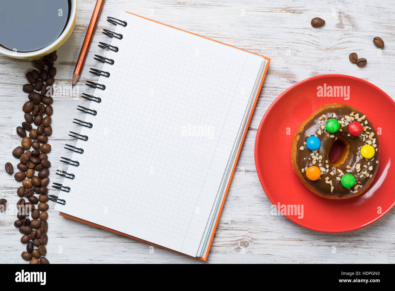 Opened notepad and cup of coffee with donut on wooden table Stock Photo ...