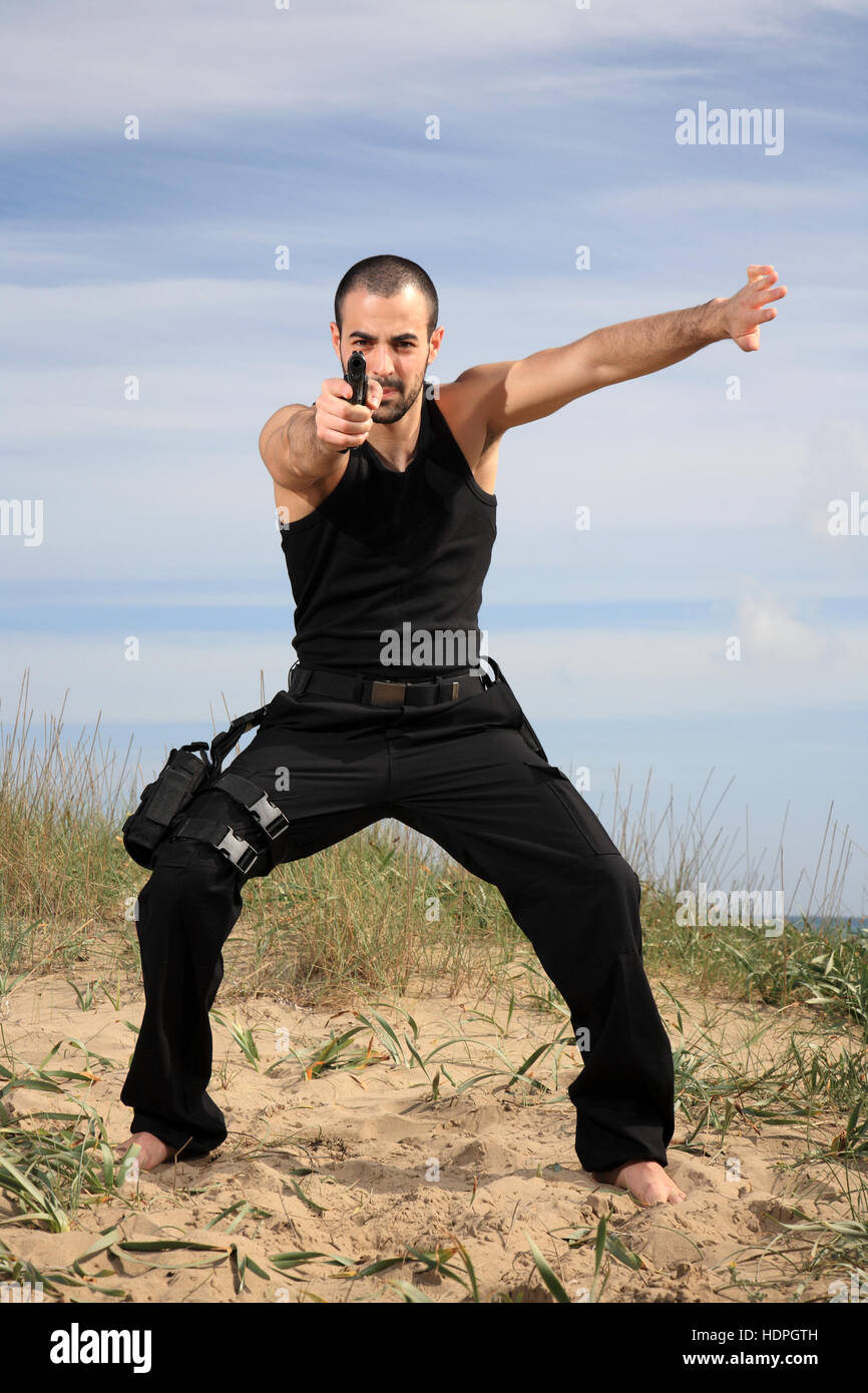 young male bodyguard holding a gun Stock Photo - Alamy