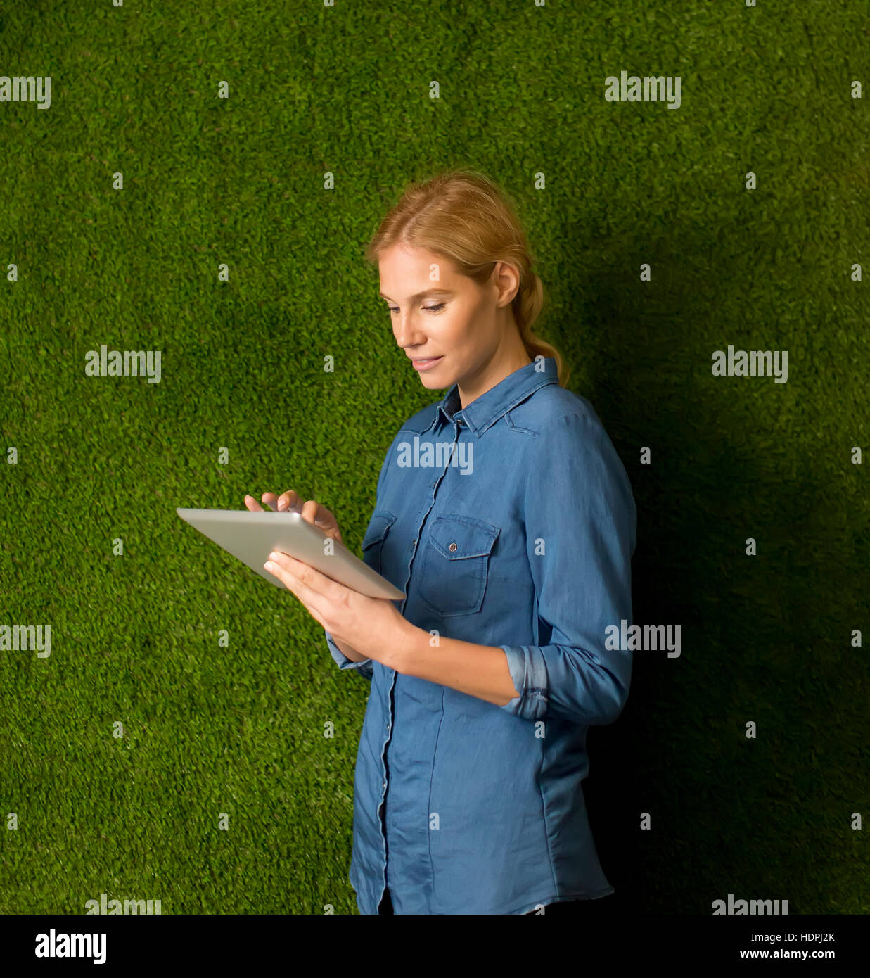 Young woman posing with tablet by green wall Stock Photo - Alamy