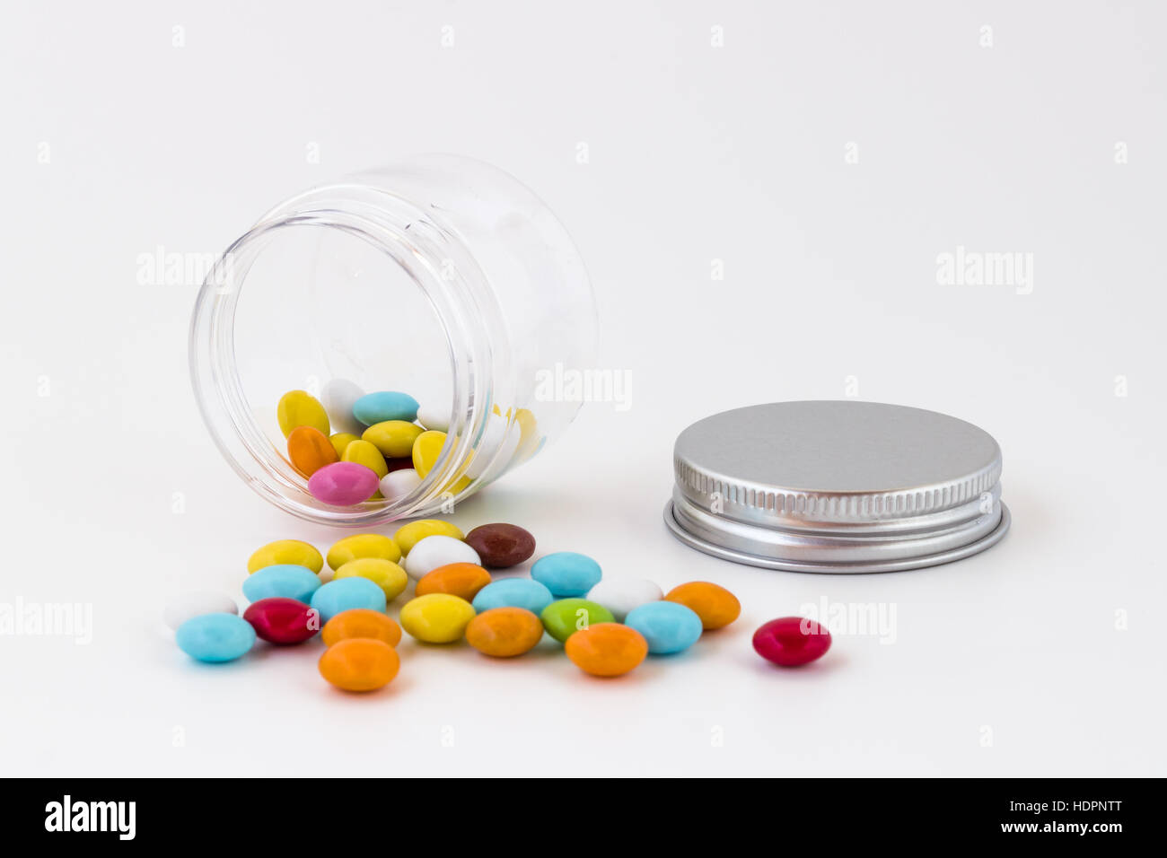 Colored Smarties scattered out of an open glass jar, isolated on white ...