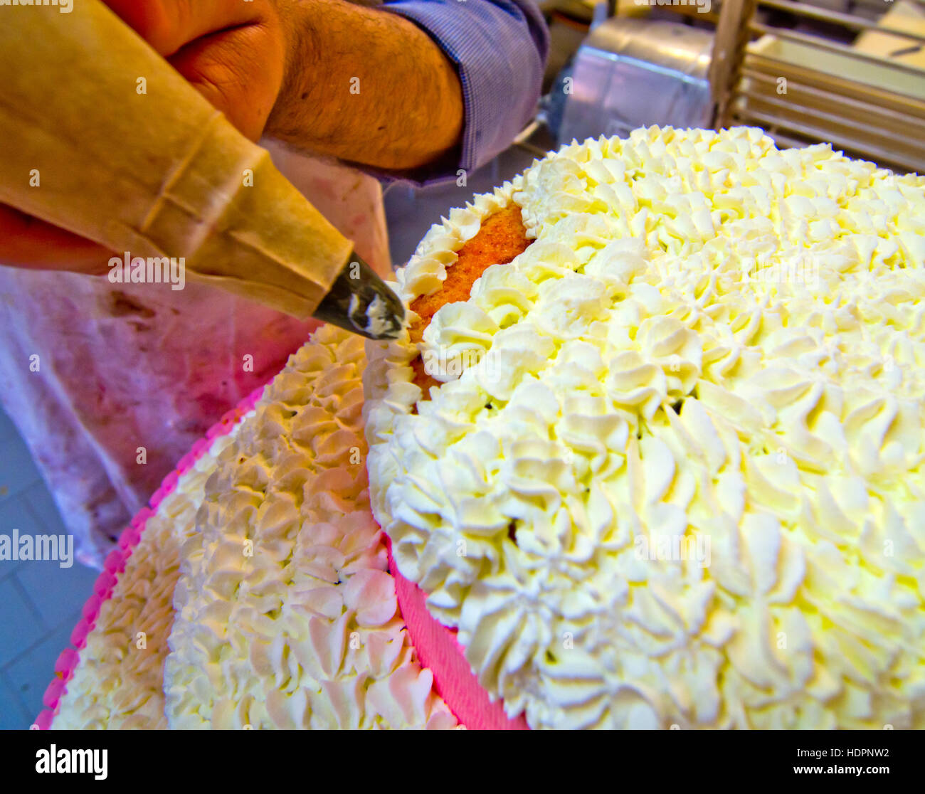 real pastry chef working in the decoration of cream on a cake for a ...