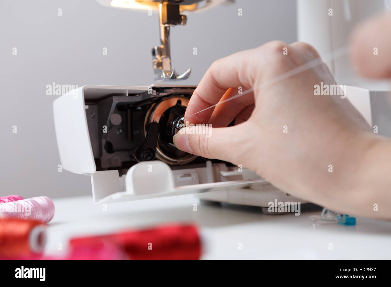 Hand with spool of sewing-machine Stock Photo - Alamy