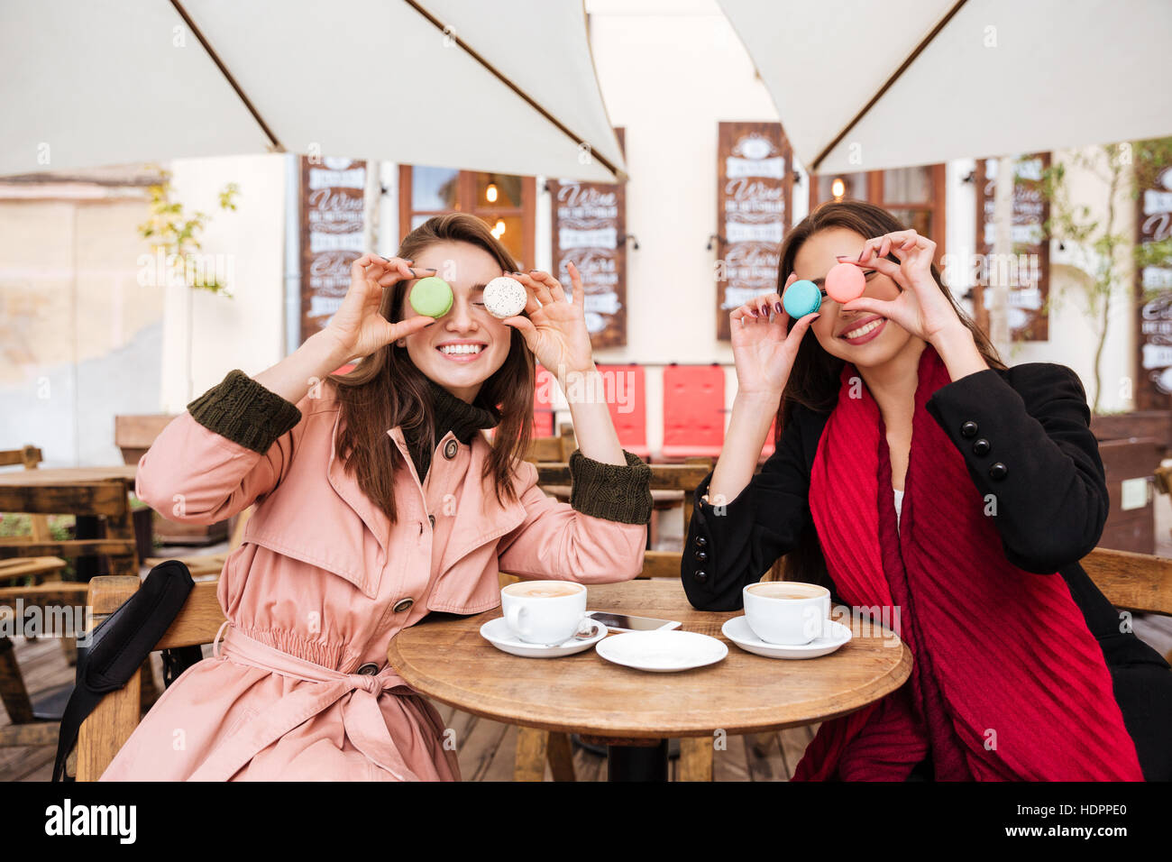 Funny models in coats at cafe. with macarons Stock Photo - Alamy