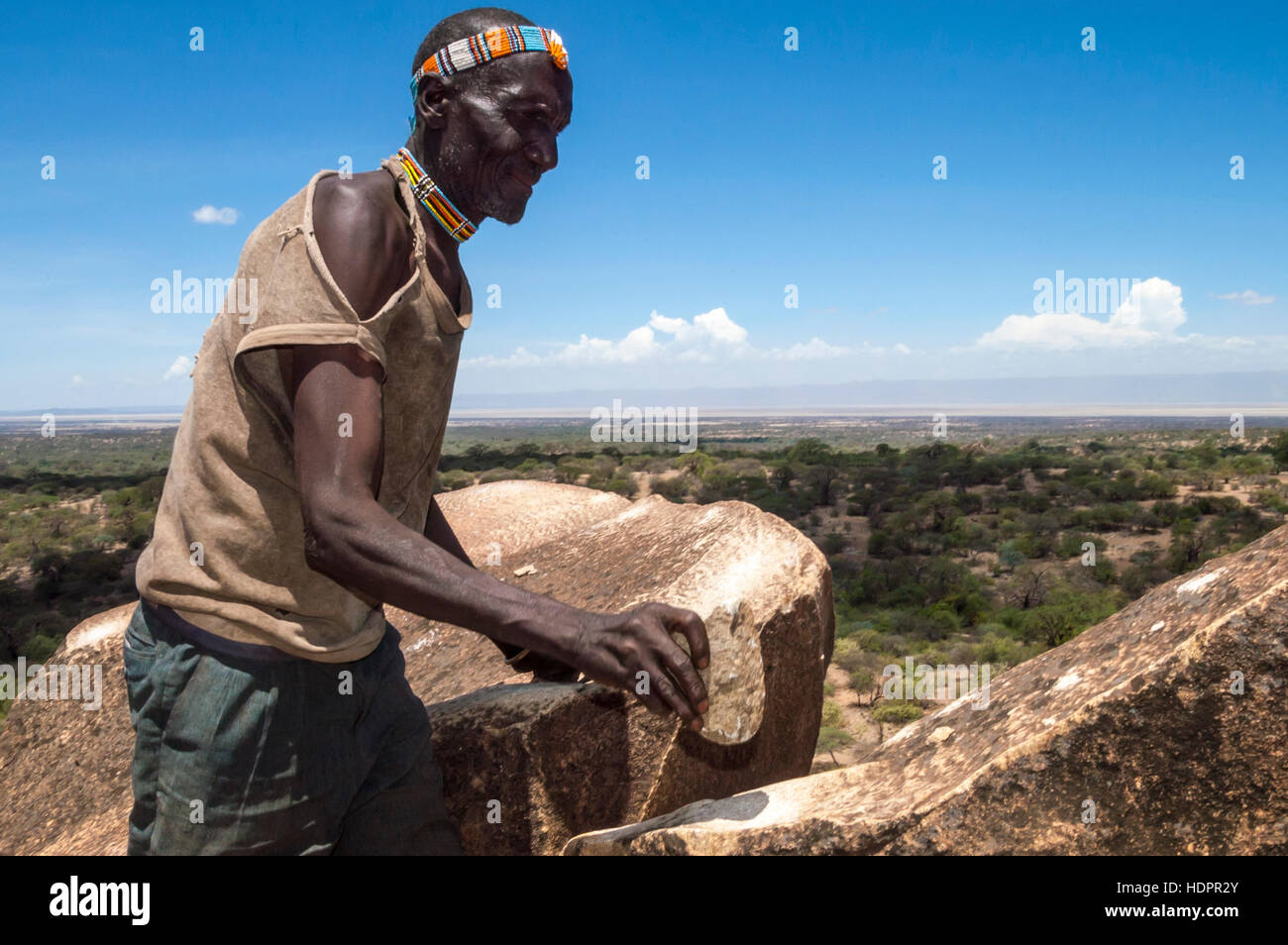 Hadzabe tribesman pounding on a resonant rock to communicate over a ...