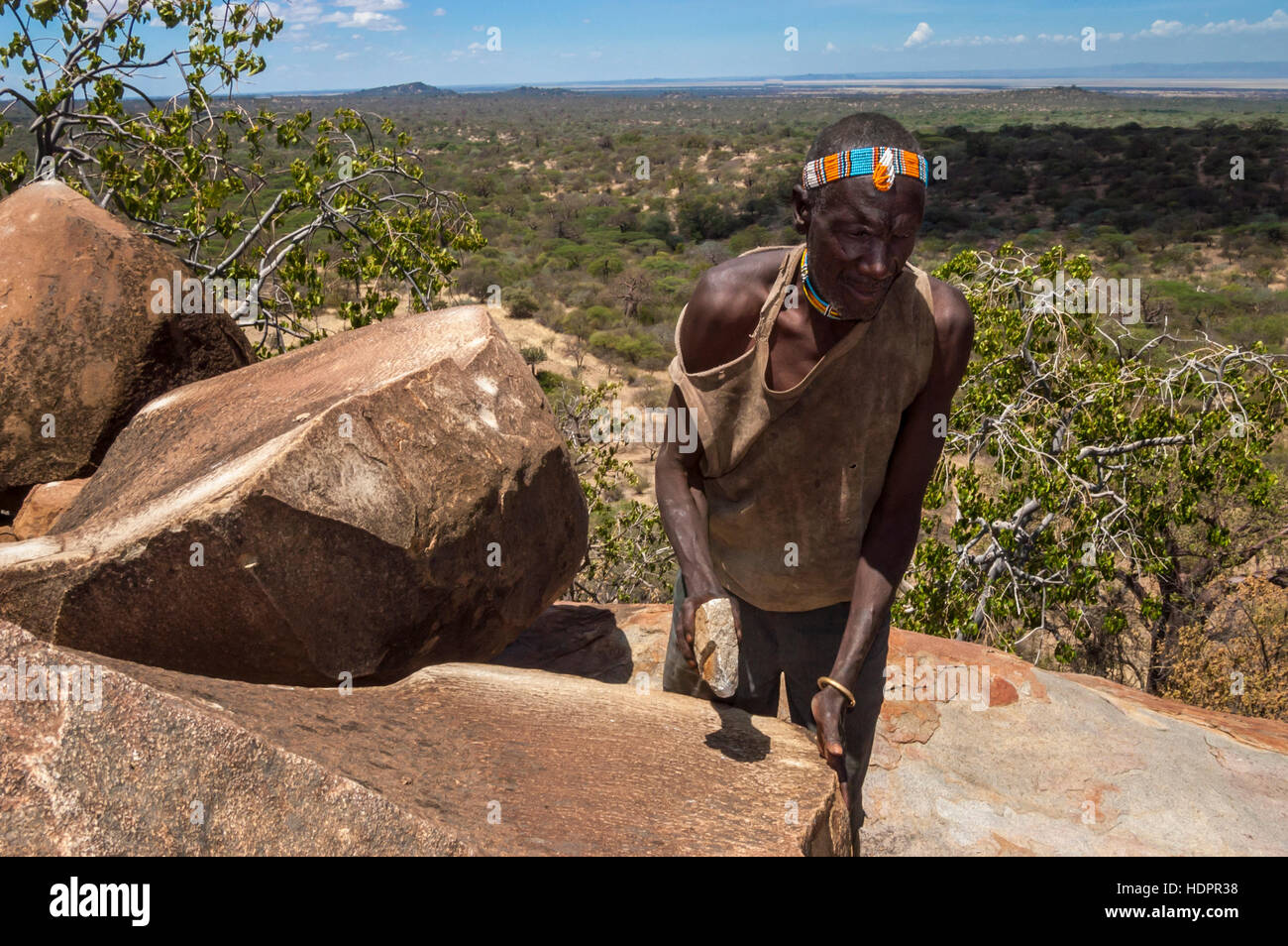 Hadzabe tribesman pounding on a resonant rock to communicate over a ...