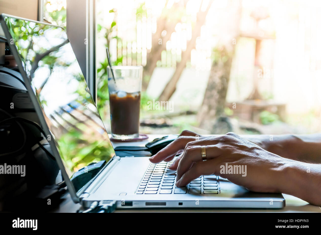 Asian man hands typing on laptop computer with blurred coffee glass and ...