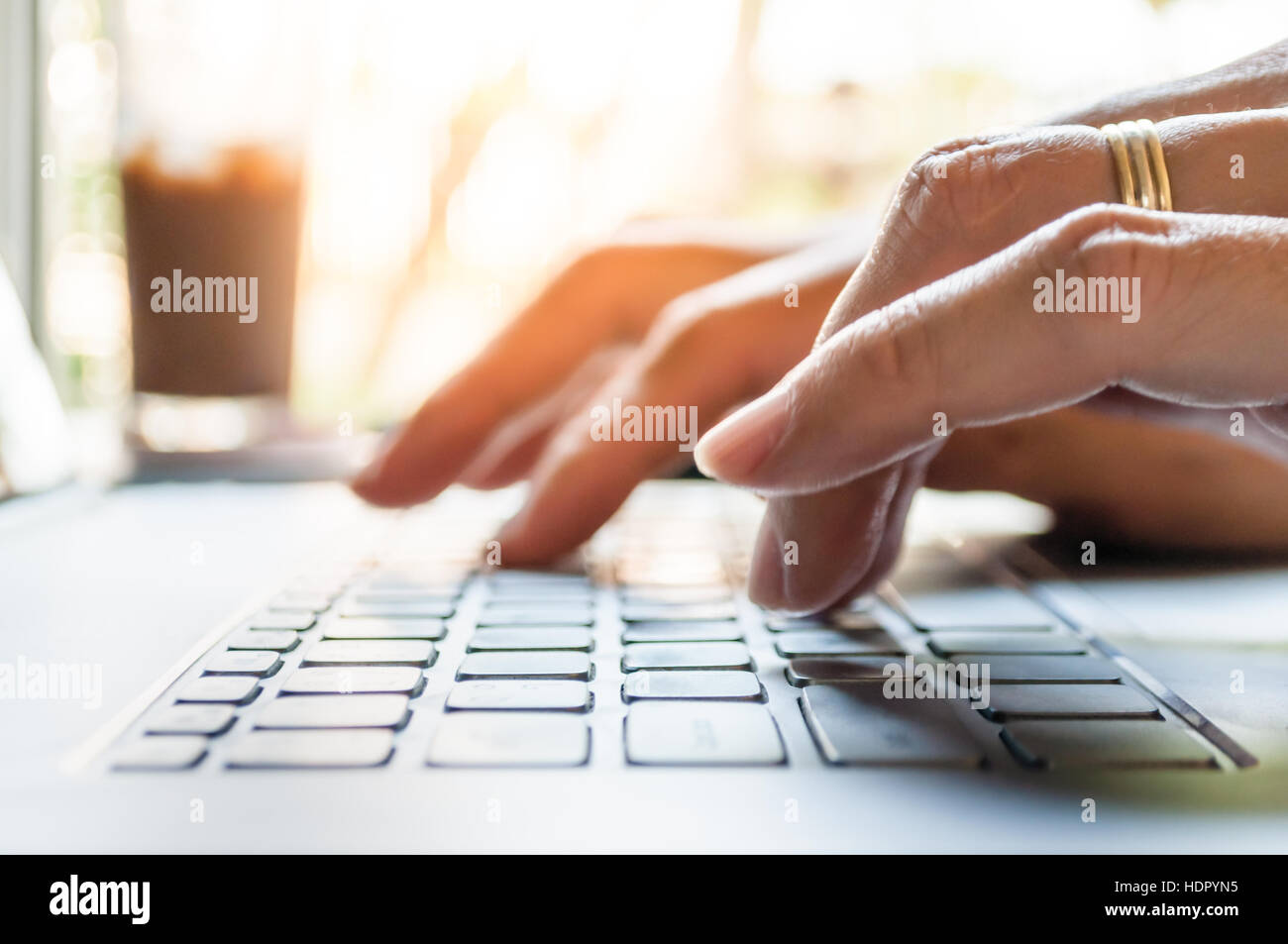 Asian man hands typing on laptop computer with blurred coffee glass and ...