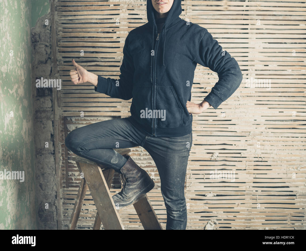 A young woman standing on a stepladder is giving thumbs up Stock Photo ...