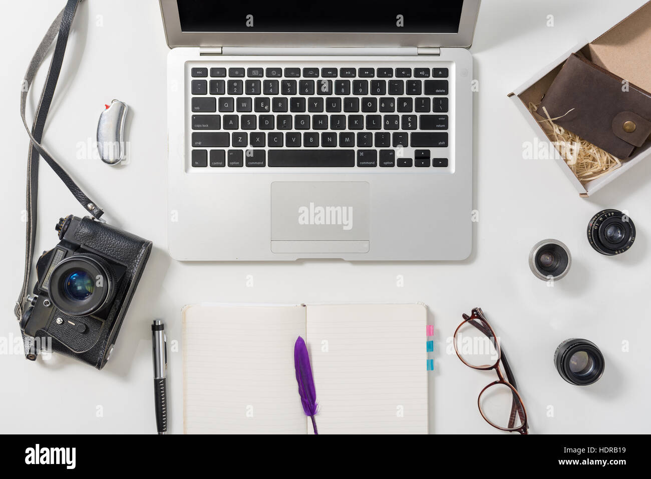Photo camera lying near the laptop on the desk Stock Photo - Alamy