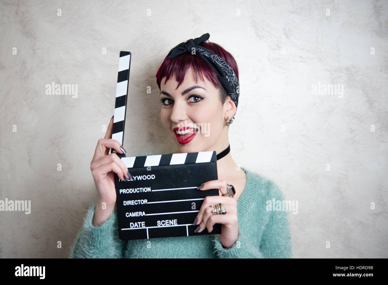Young alternative girl smiling face and posing with movie clapper board ...