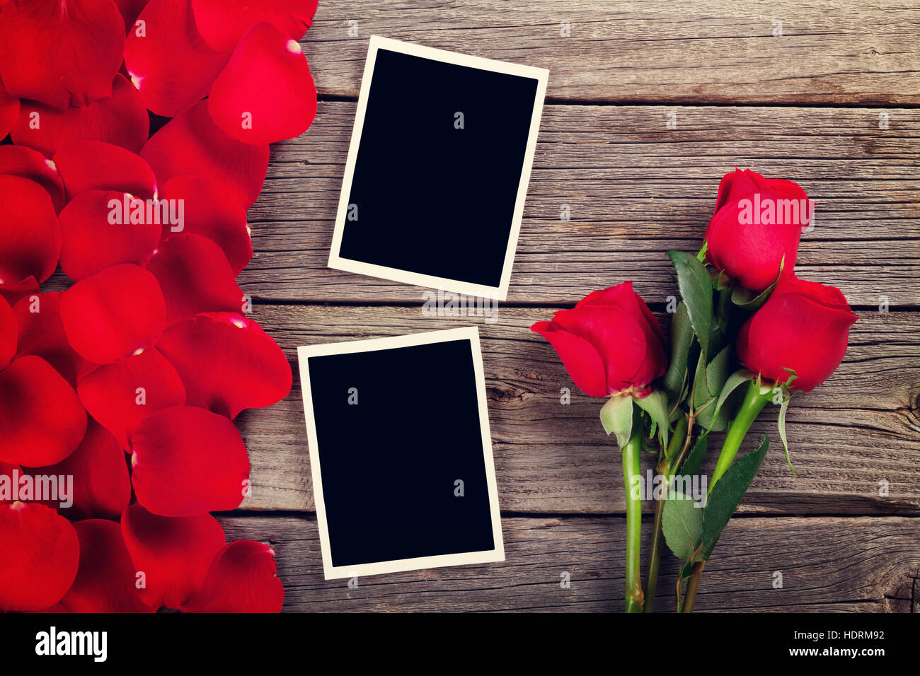 Red roses, photo frames and petals over wooden table. Toned Stock Photo ...
