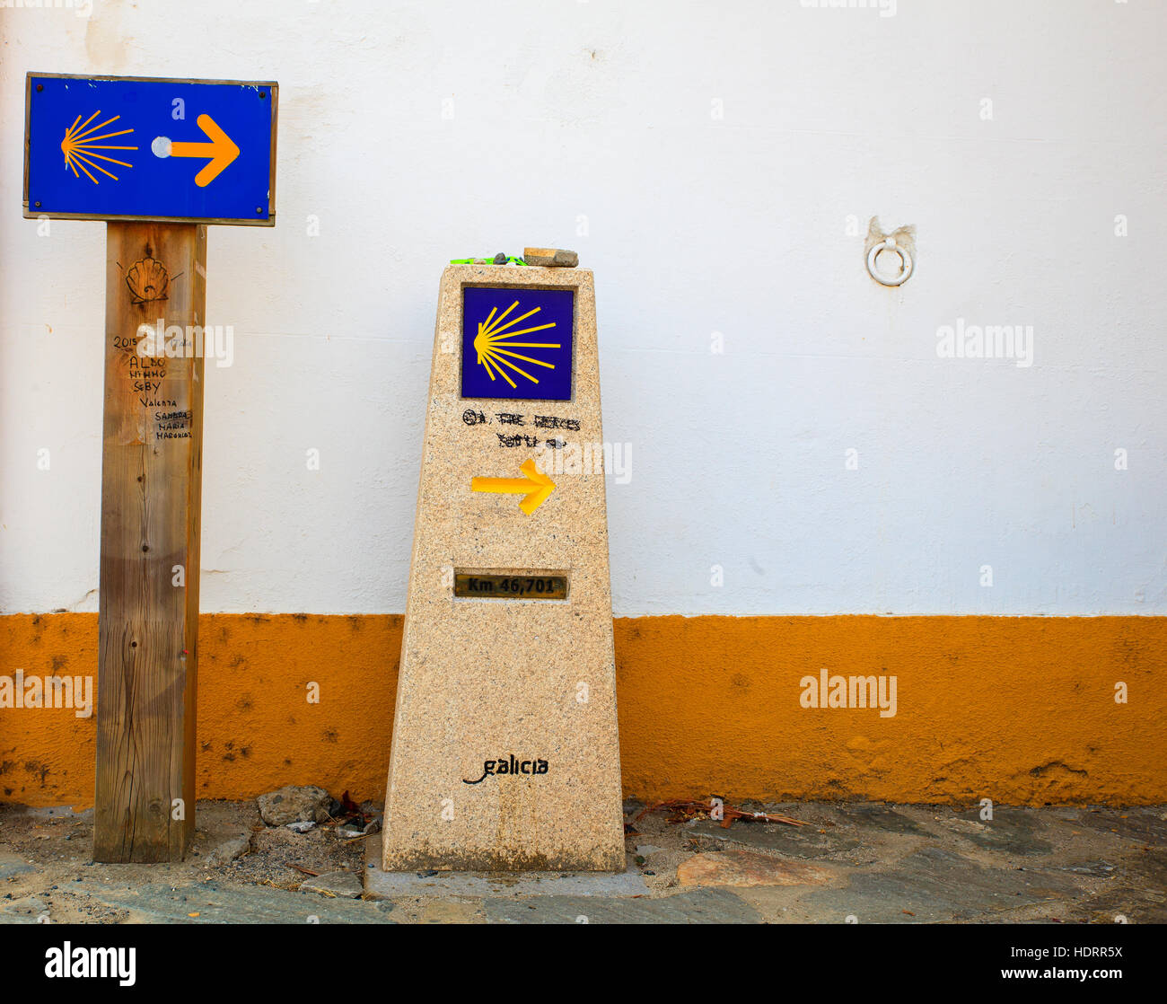 Stone signal with yellow arrow and shell, symbols of the way of St ...