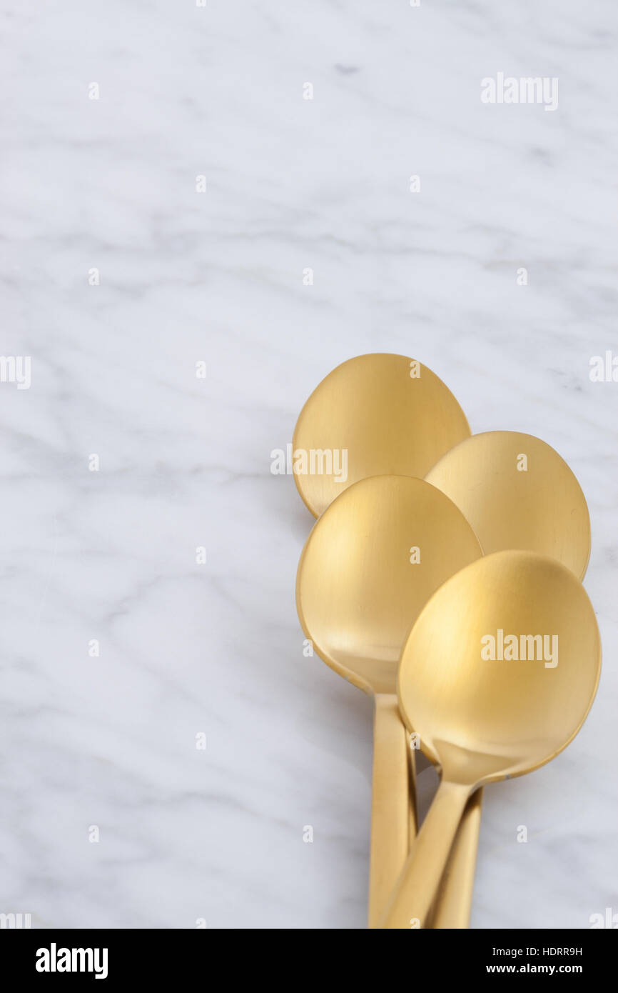 golden spoon set styled on antique carrara marble Stock Photo - Alamy
