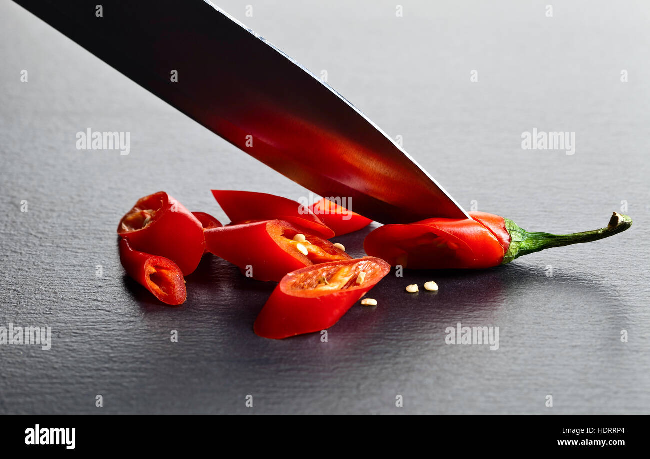 Knife and red chilli pepper on black table Stock Photo - Alamy