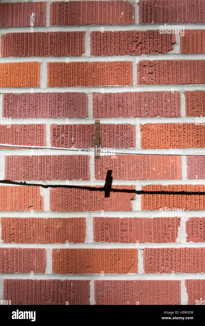 Vertical image of single clothes pin on a laundry line against a red ...