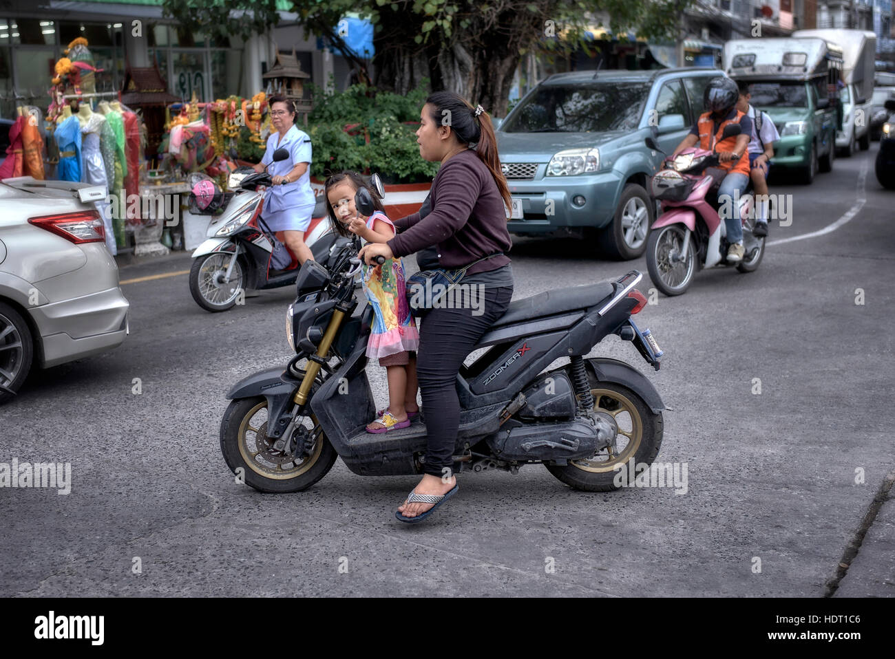 Woman transporting child on her motorbike through traffic. Thailand S ...