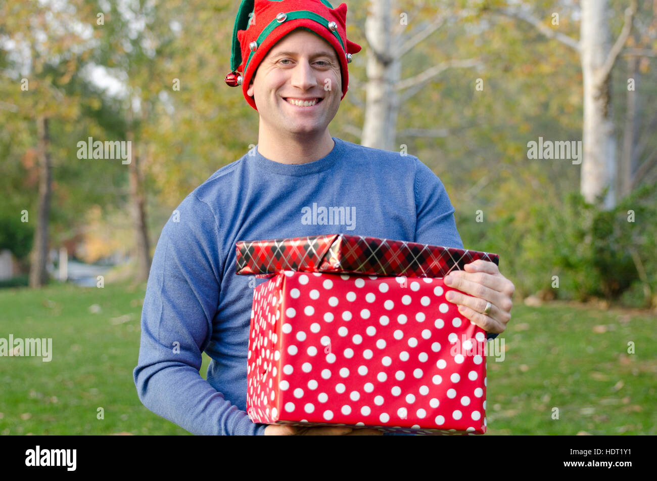 Happy man carrying gifts and wearing a Christmas hat Stock Photo - Alamy