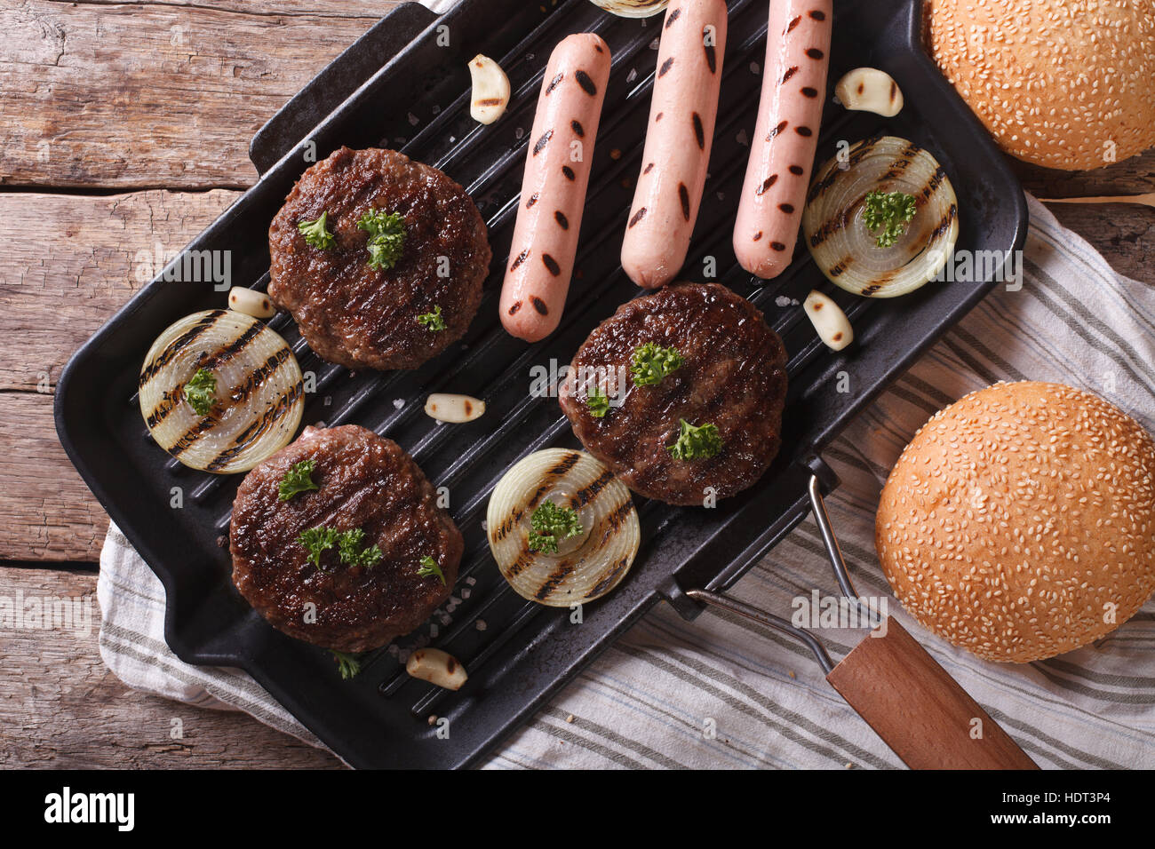 Burger and sausages on a grill pan. horizontal view from above close up ...
