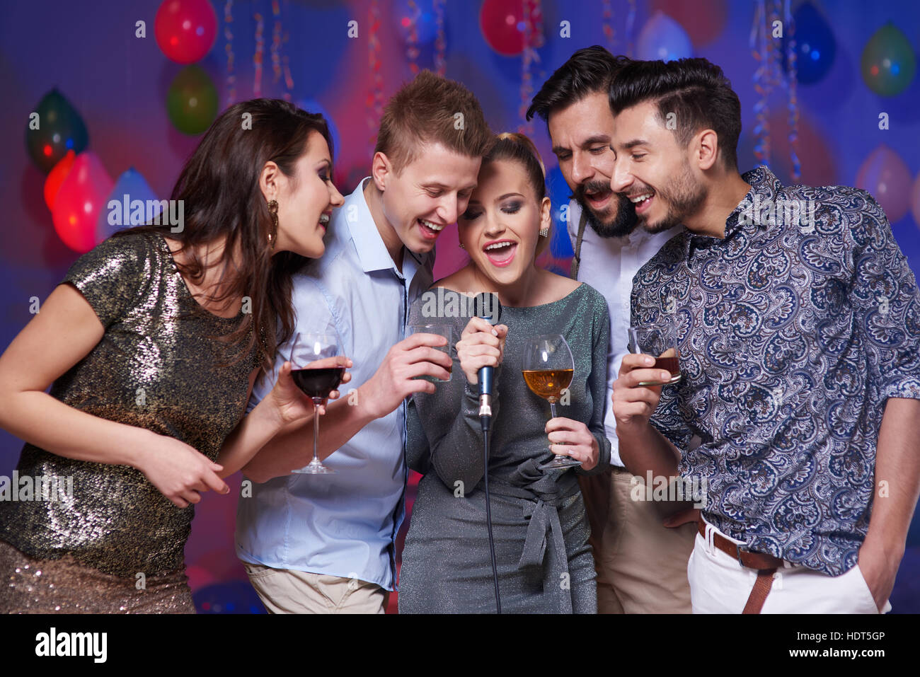 Group of friends doing karaoke show Stock Photo - Alamy