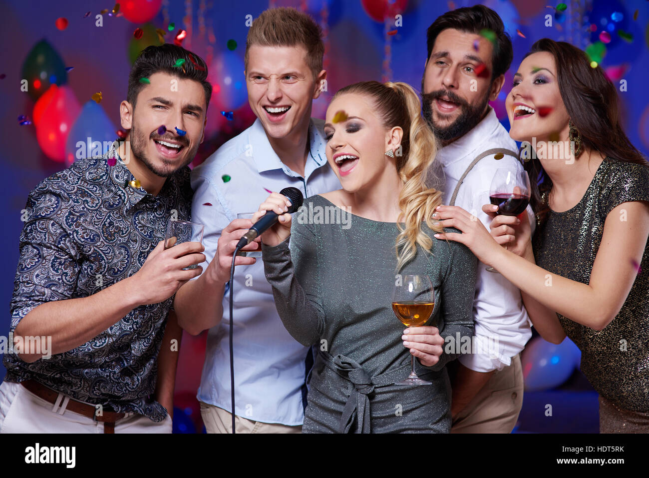 Group of friends singing karaoke at party Stock Photo - Alamy