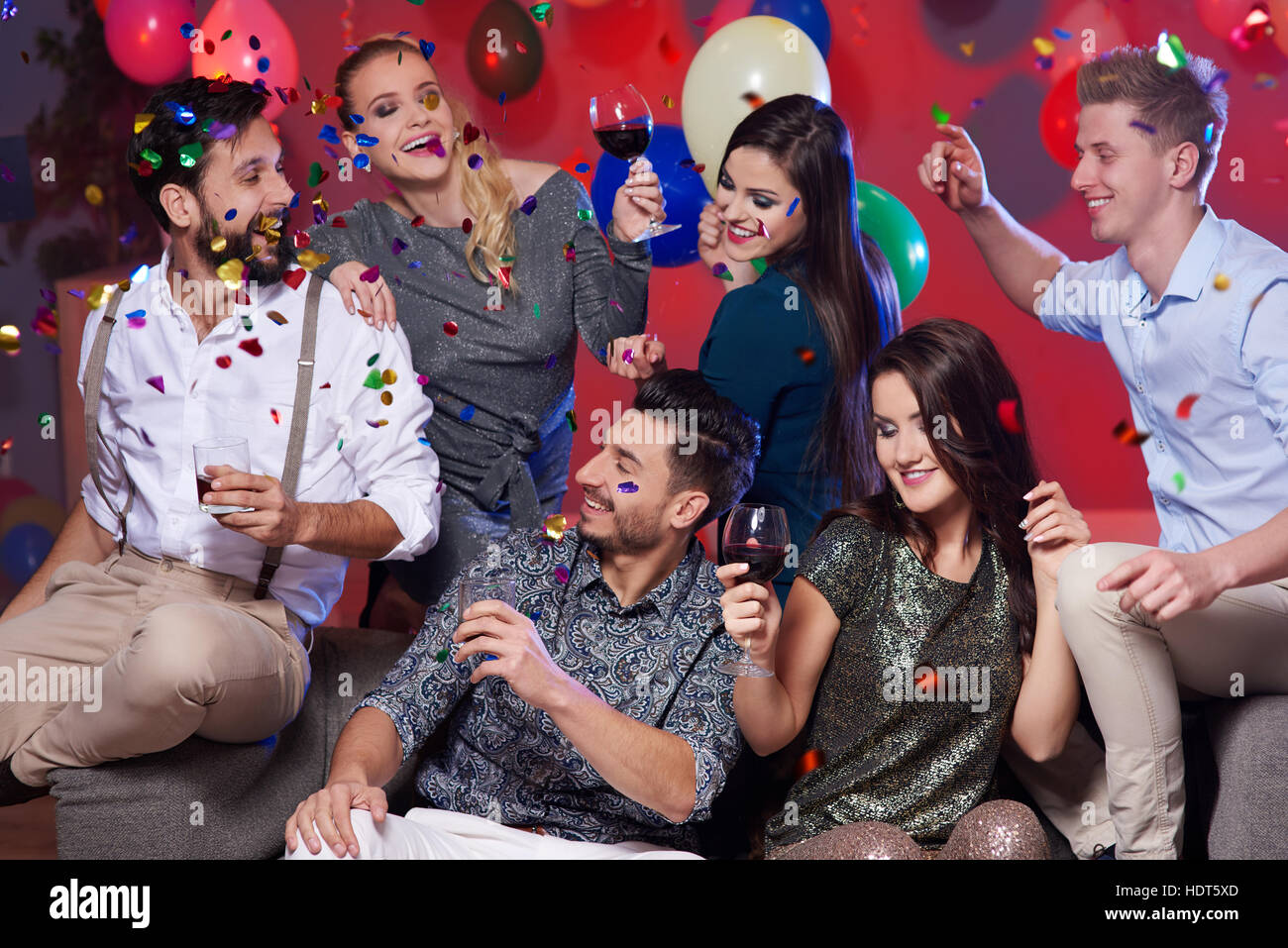 Couples enjoying party with drinks among colorful confetti Stock Photo ...
