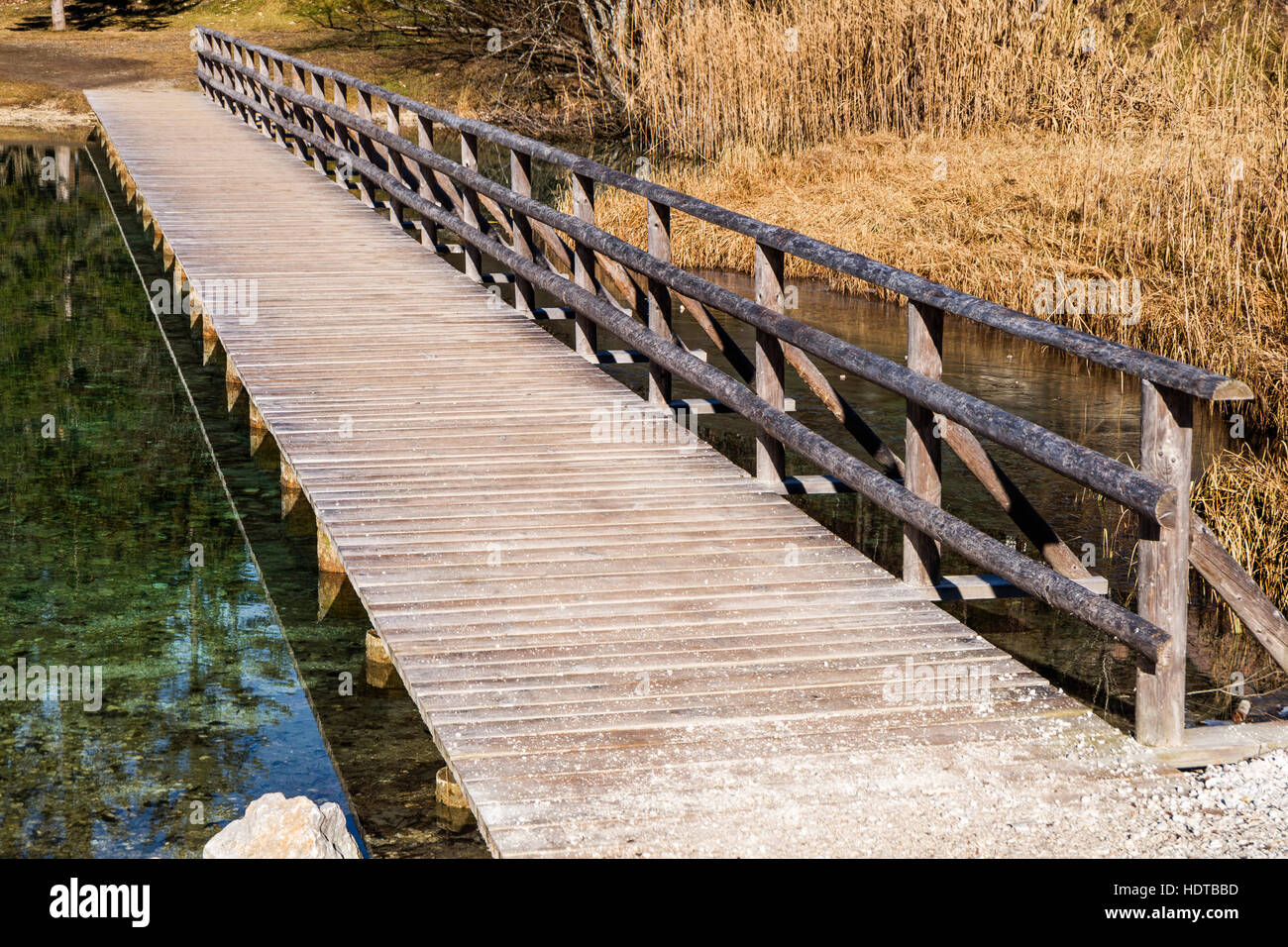 Wooden bridge with railing on one side, over part of lake Jasna in ...