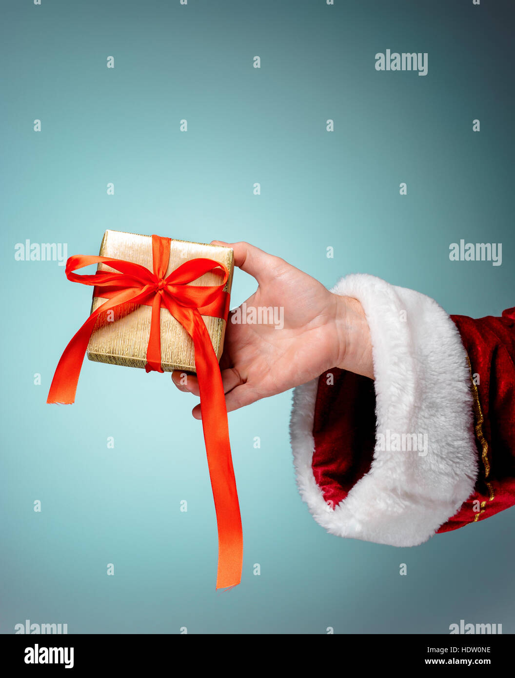 The hand of santa claus holding a gift on blue background Stock Photo ...