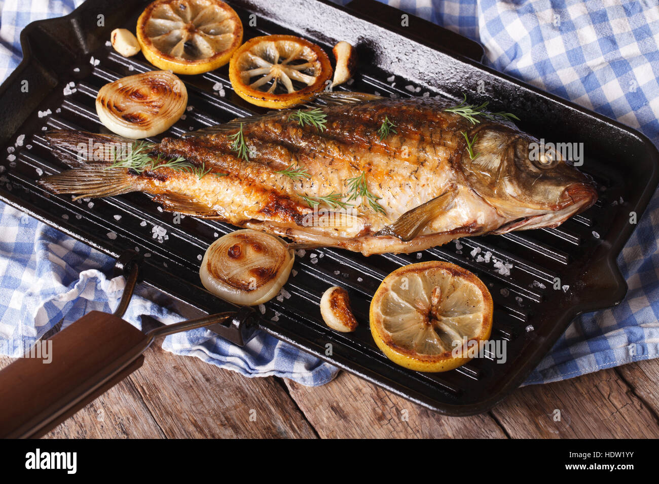 grilled fish carp with lemon on a frying pan grill, horizontal close-up ...