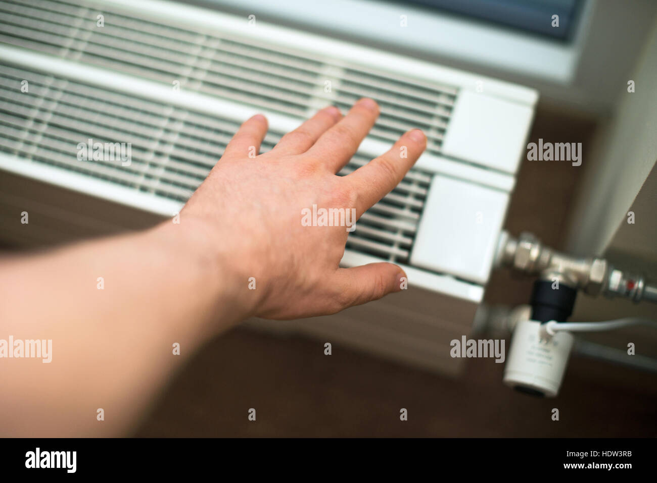 Man's hand checking temperature of heating radiator Stock Photo - Alamy