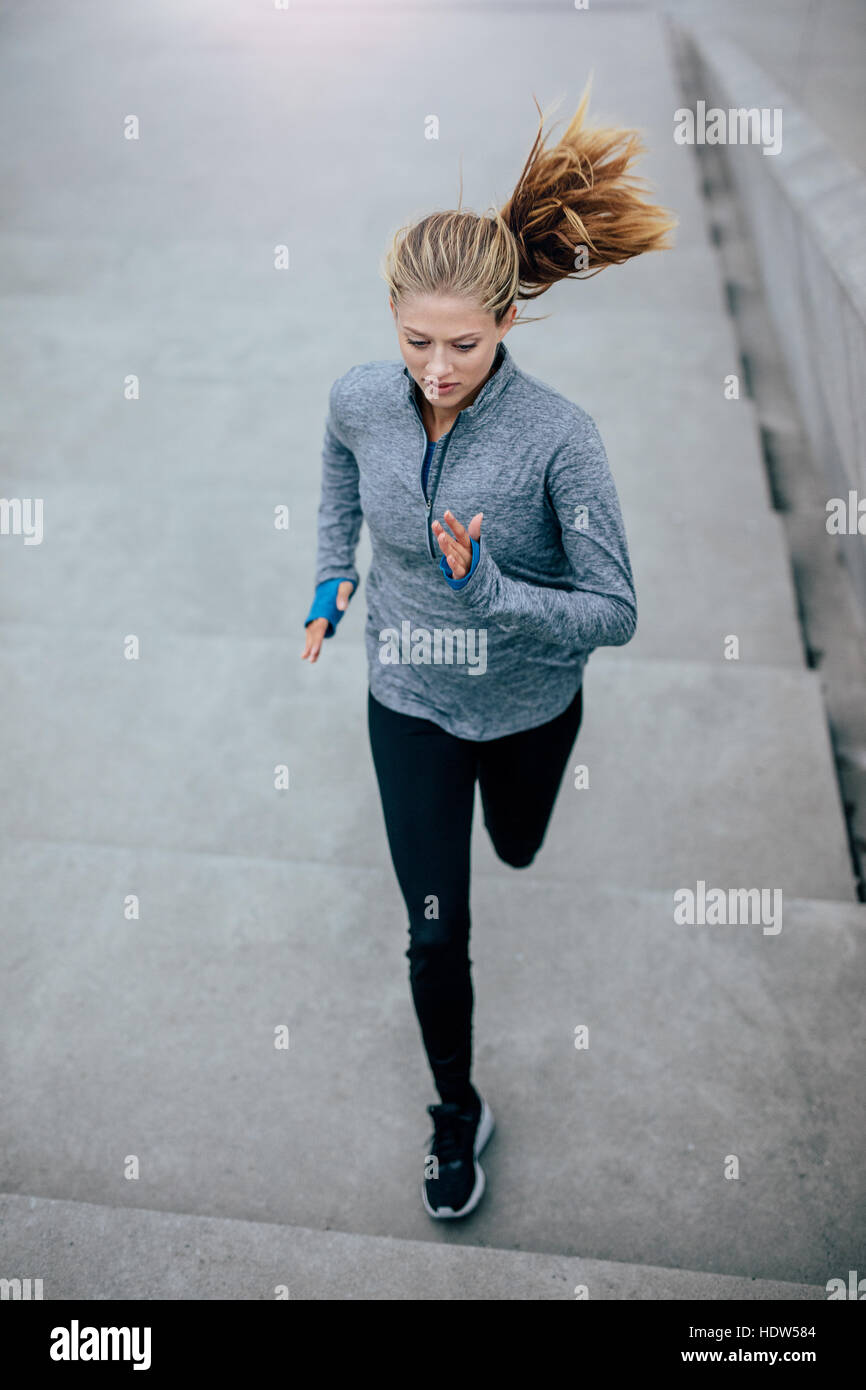 Top view shot of health conscious woman running upstairs on steps ...