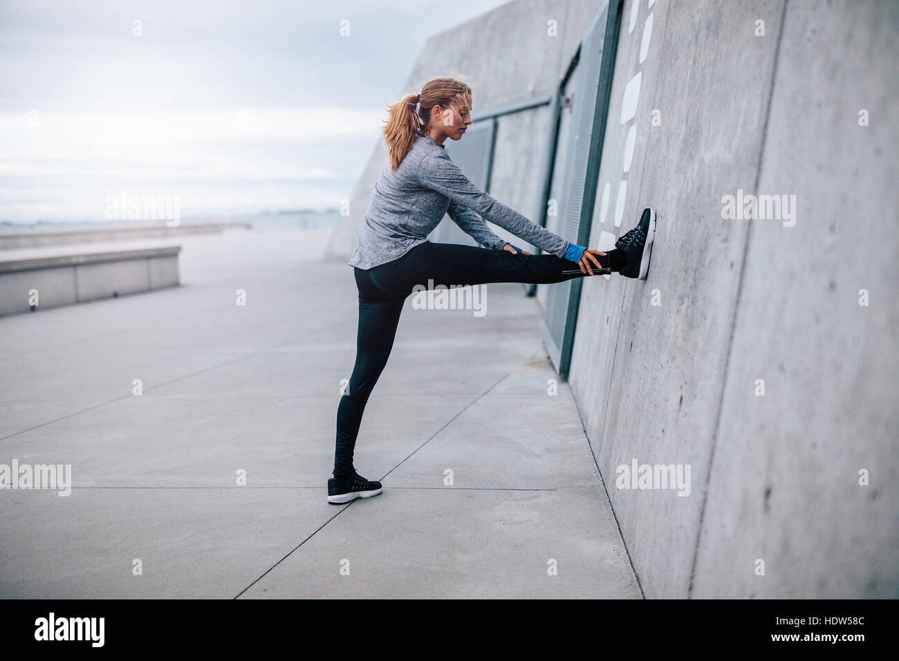 Side view shot of young fitness woman stretching outdoors. Female ...