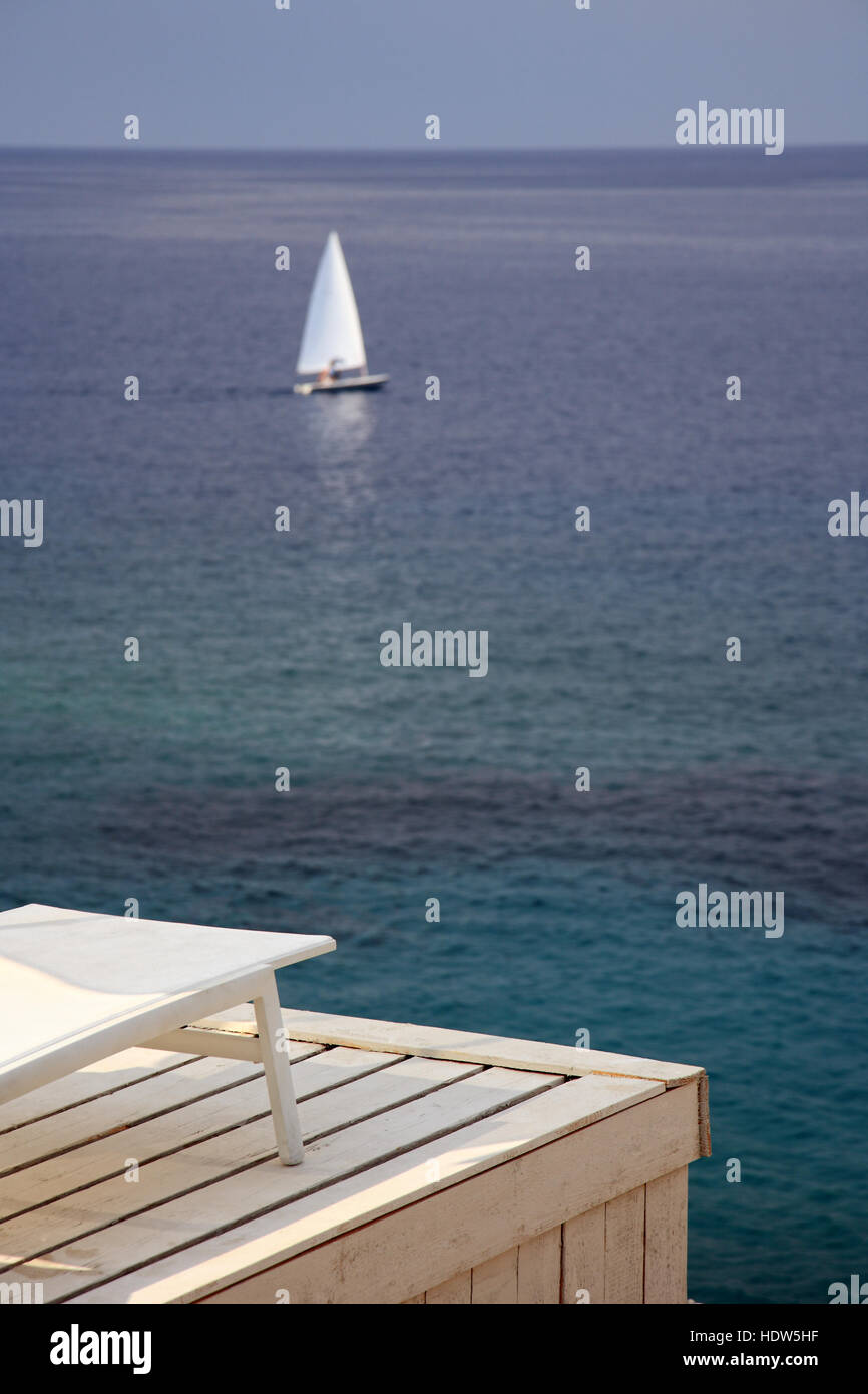 sunbed with nice view and a sailing boat in the water Stock Photo - Alamy