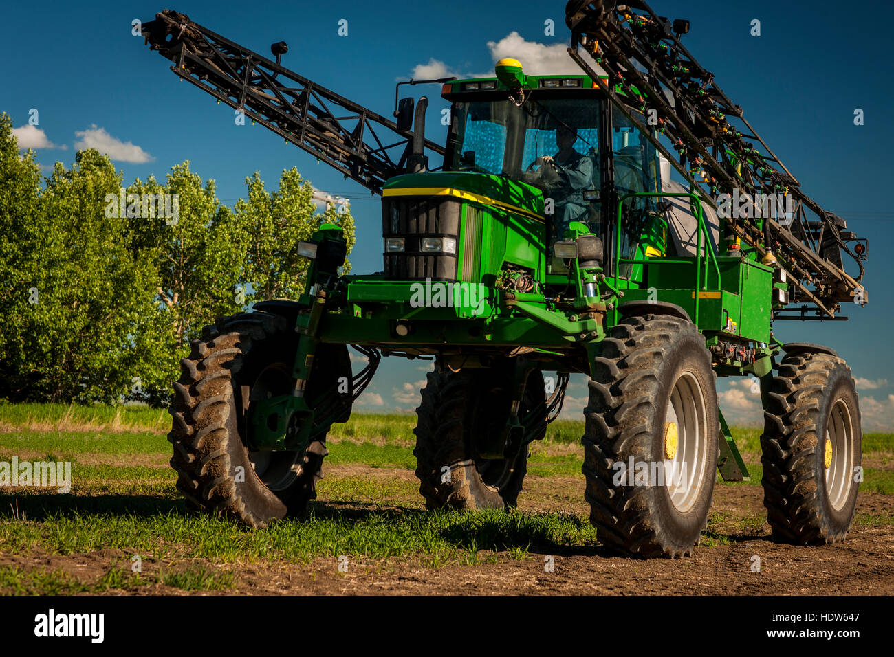 A farmer drives a sprayer across a farm field; Herschel, Saskatchewan ...
