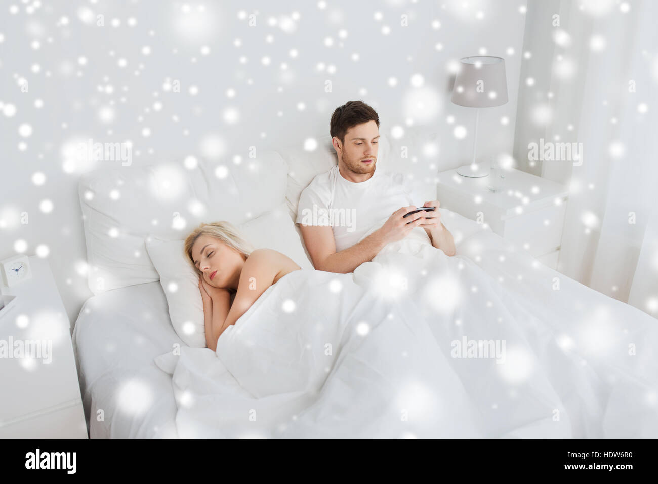 man texting message while woman is sleeping in bed Stock Photo - Alamy