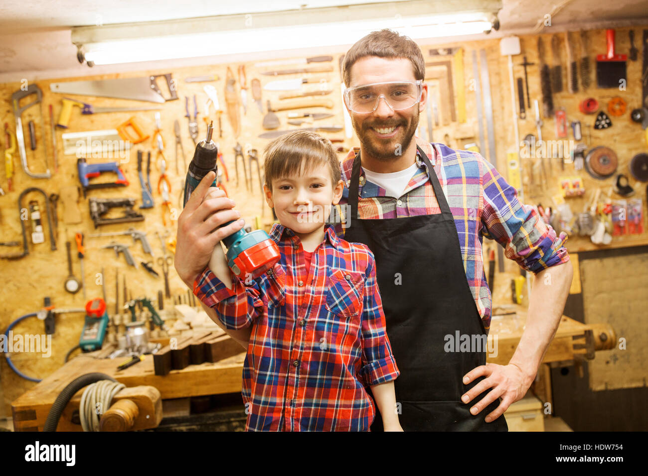 father and son with drill working at workshop Stock Photo - Alamy
