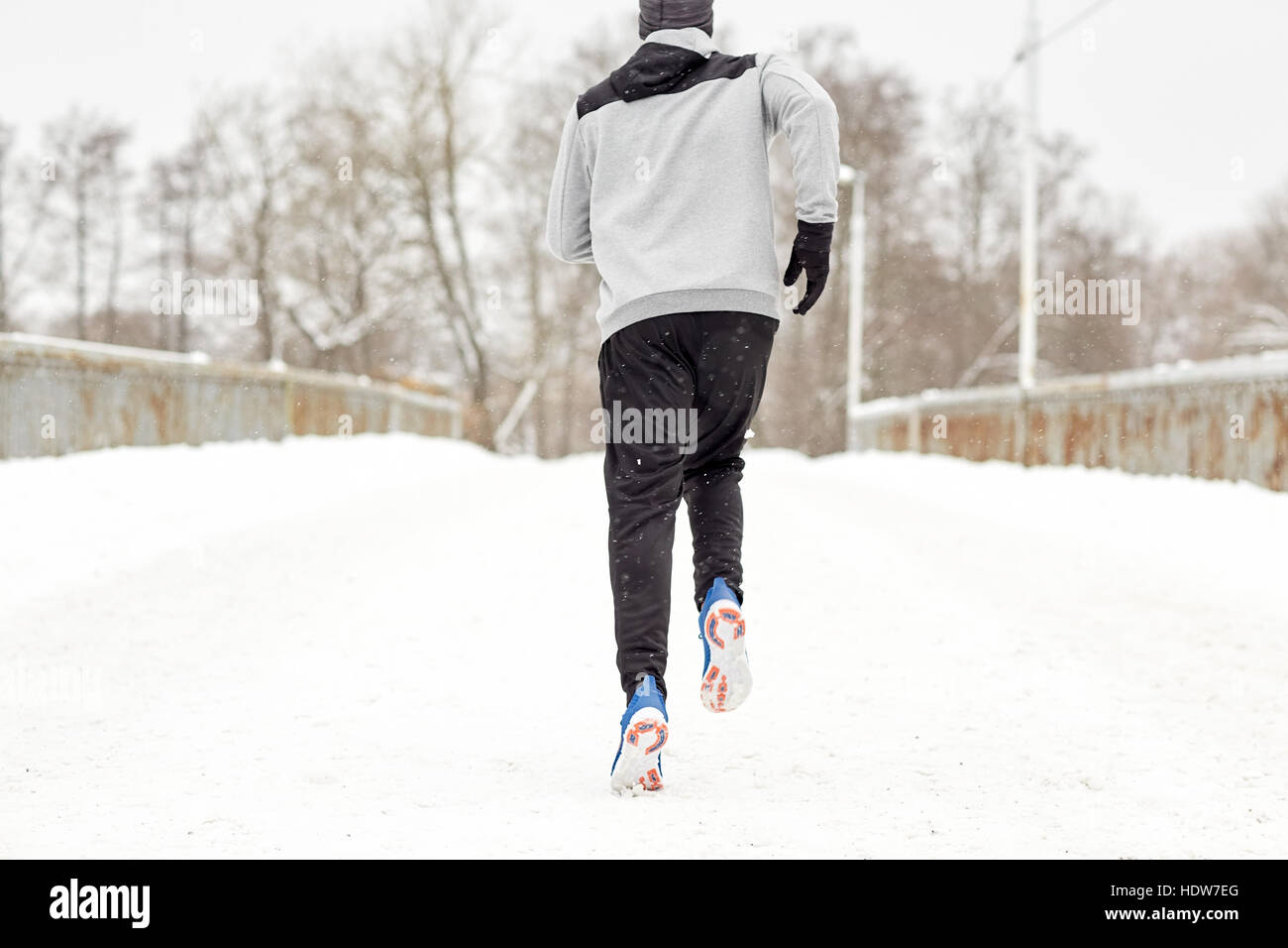 man running along snow covered winter bridge road Stock Photo - Alamy