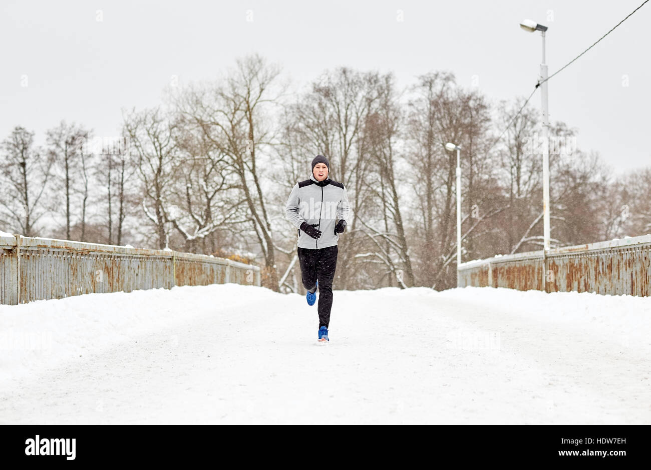 man running along snow covered winter bridge road Stock Photo - Alamy