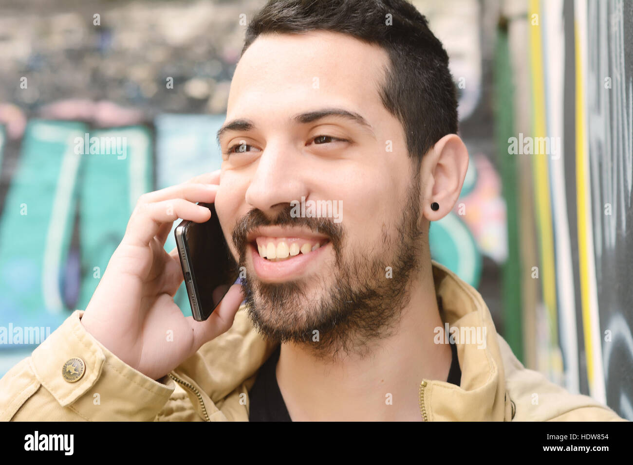 Handsome young latin man talking on the phone. Trendy and urban scene ...
