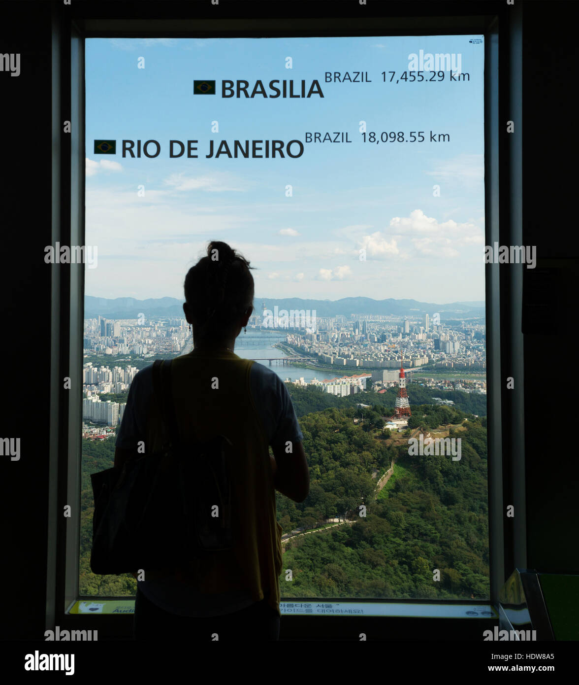 A woman stands at the window of Seoul Tower with a view of the city of ...