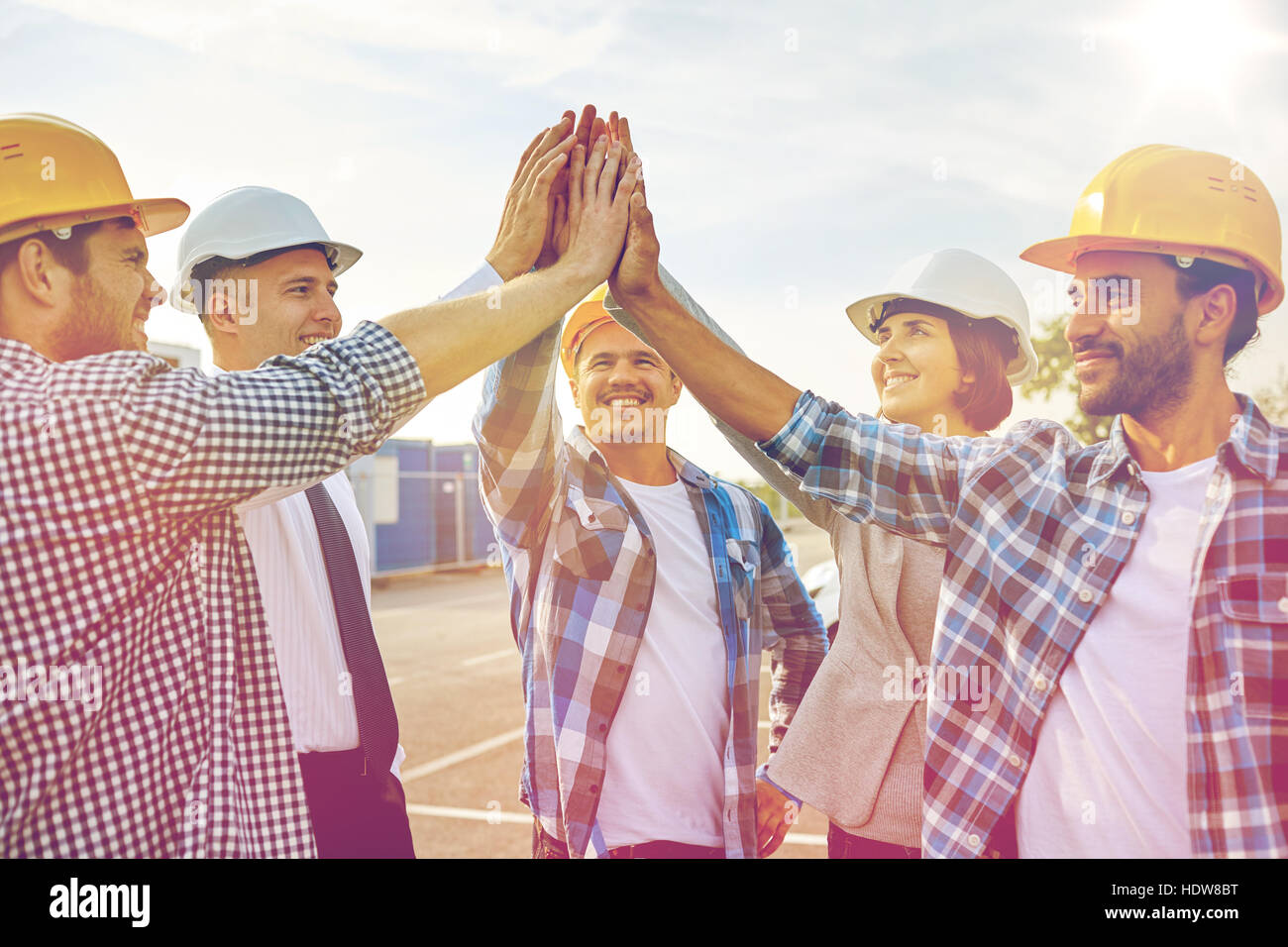 close up of builders in hardhats making high five Stock Photo - Alamy
