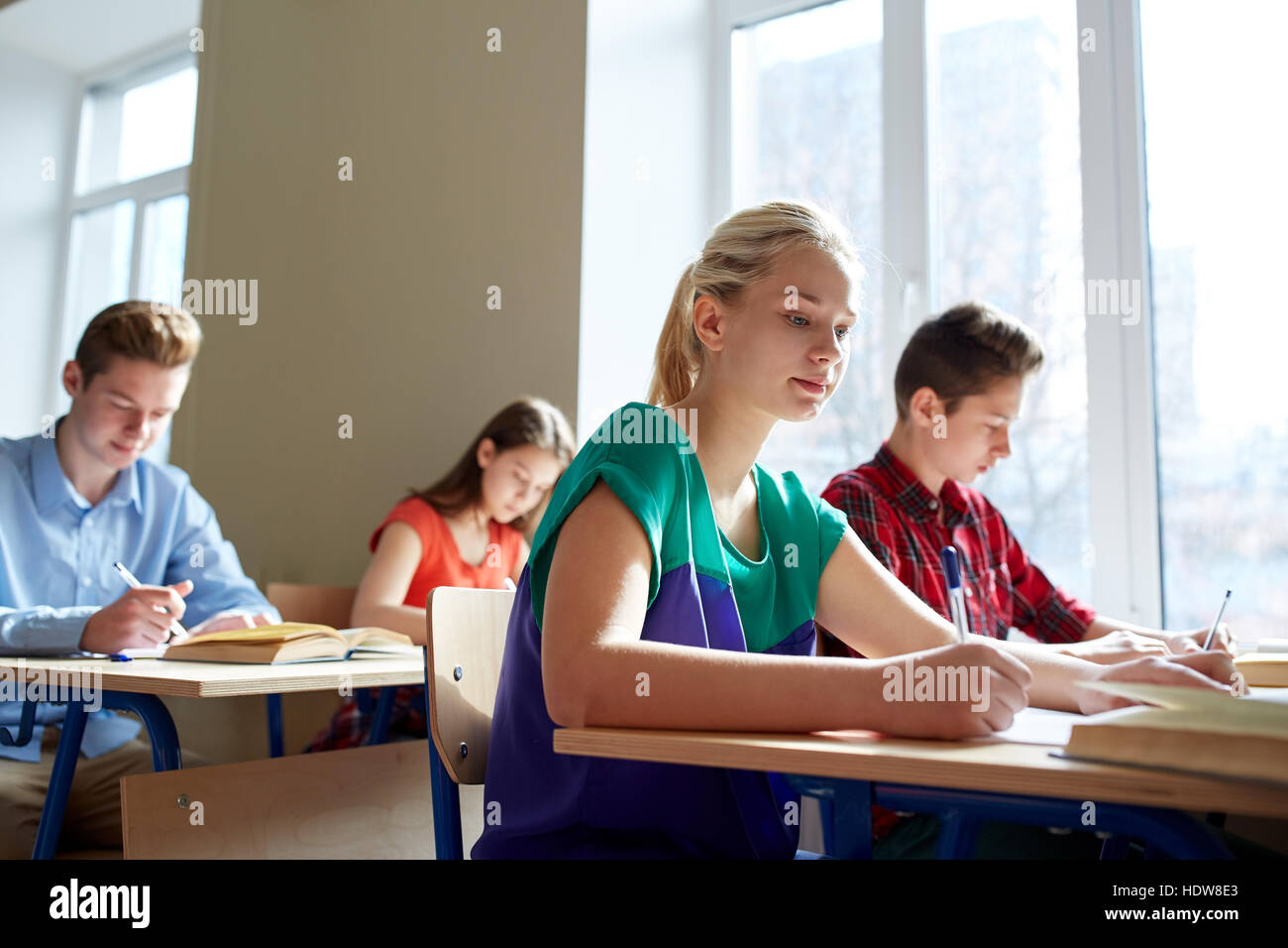 group of students with books writing school test Stock Photo - Alamy